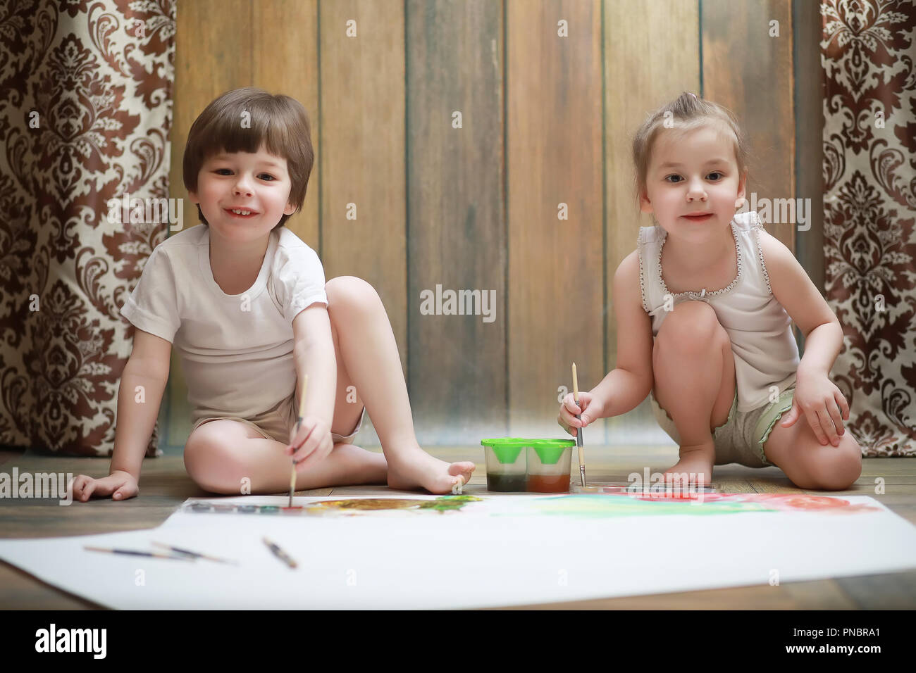Little children paint on a large sheet of paper Stock Photo - Alamy