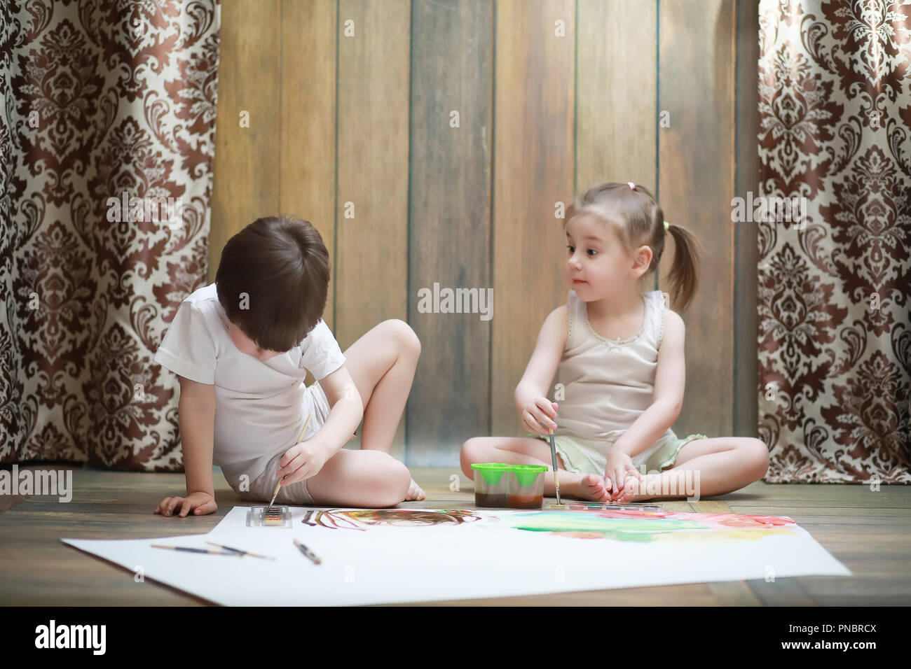 Little children paint on a large sheet of paper Stock Photo - Alamy