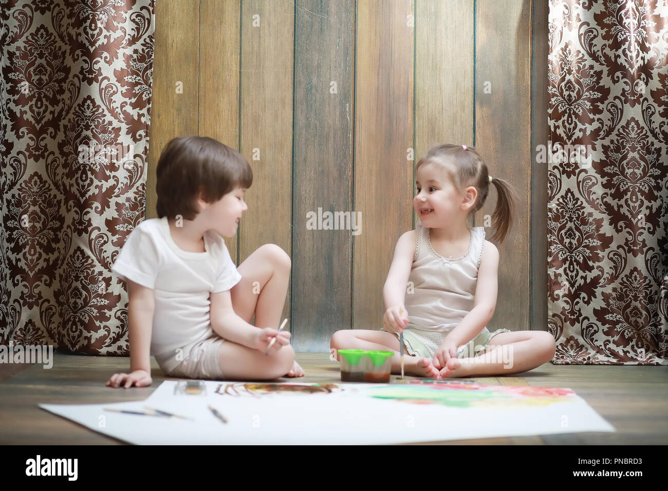 Little children paint on a large sheet of paper Stock Photo - Alamy