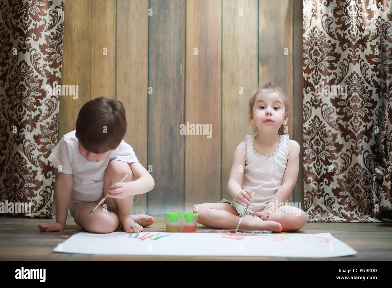 Little children paint on a large sheet of paper Stock Photo - Alamy
