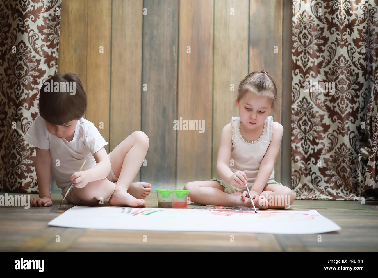 Little children paint on a large sheet of paper Stock Photo - Alamy