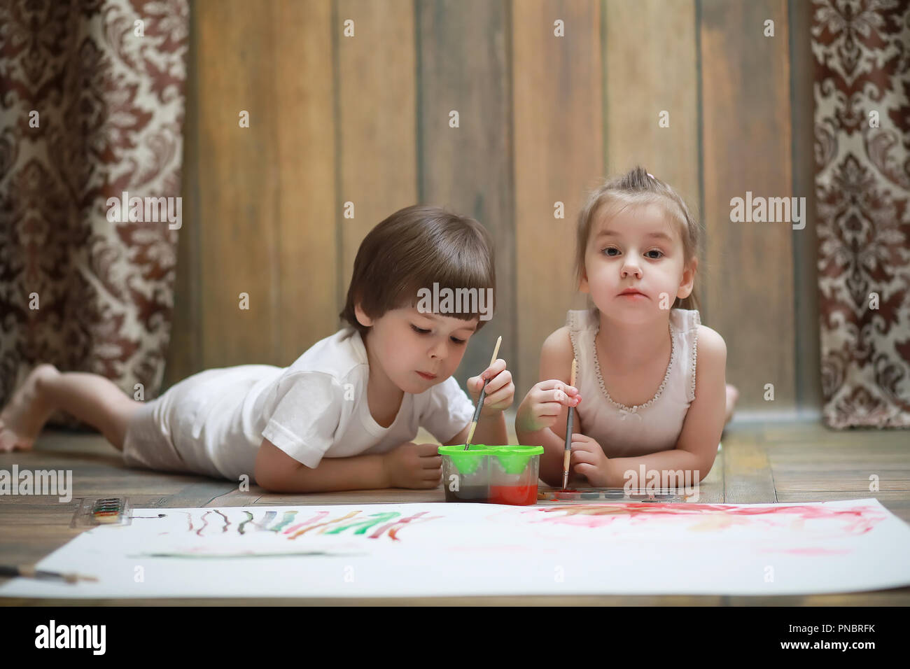 Little children paint on a large sheet of paper Stock Photo - Alamy