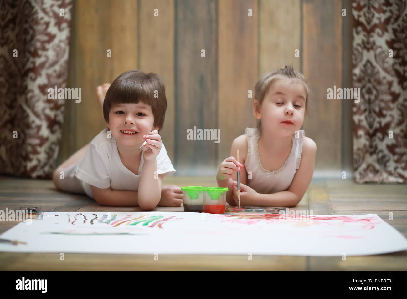Little children paint on a large sheet of paper Stock Photo - Alamy