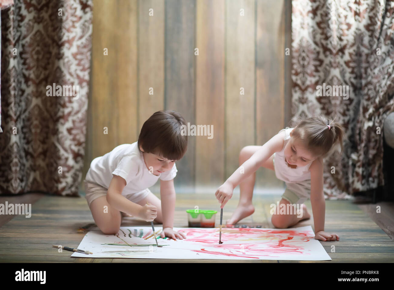 Little children paint on a large sheet of paper Stock Photo - Alamy