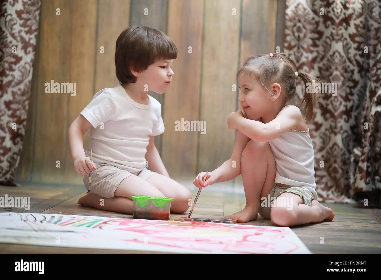 Little children paint on a large sheet of paper Stock Photo - Alamy