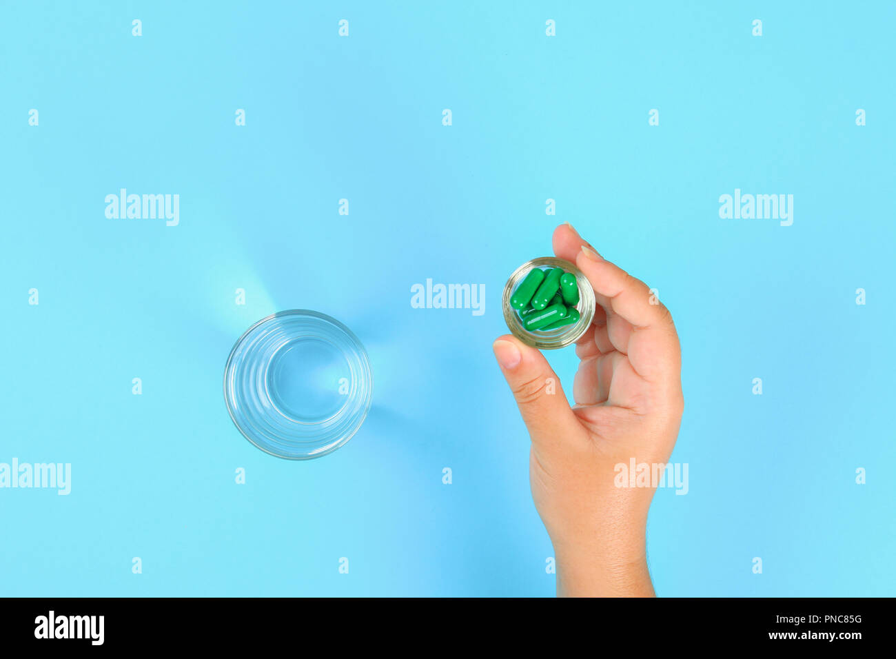 Swallowing tablets. Pills and a glass of water against a blue table ...