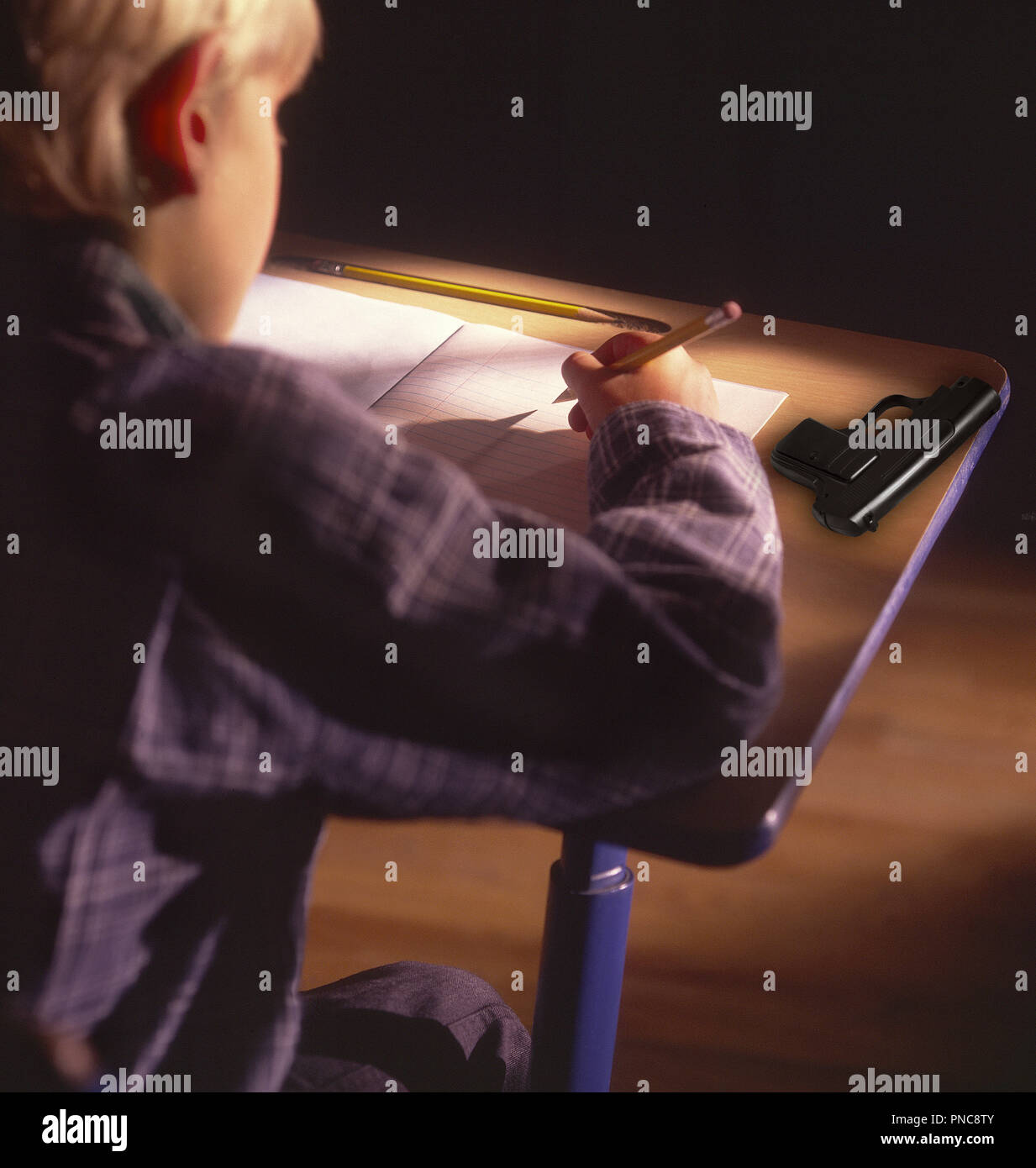 young boy at school desk with gun Stock Photo - Alamy