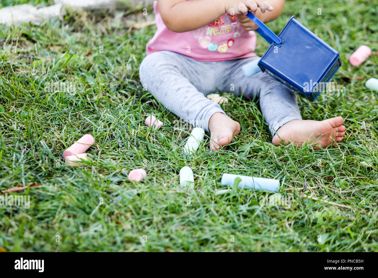 Details of a young girl playing with colored chalk on the grass, in the ...