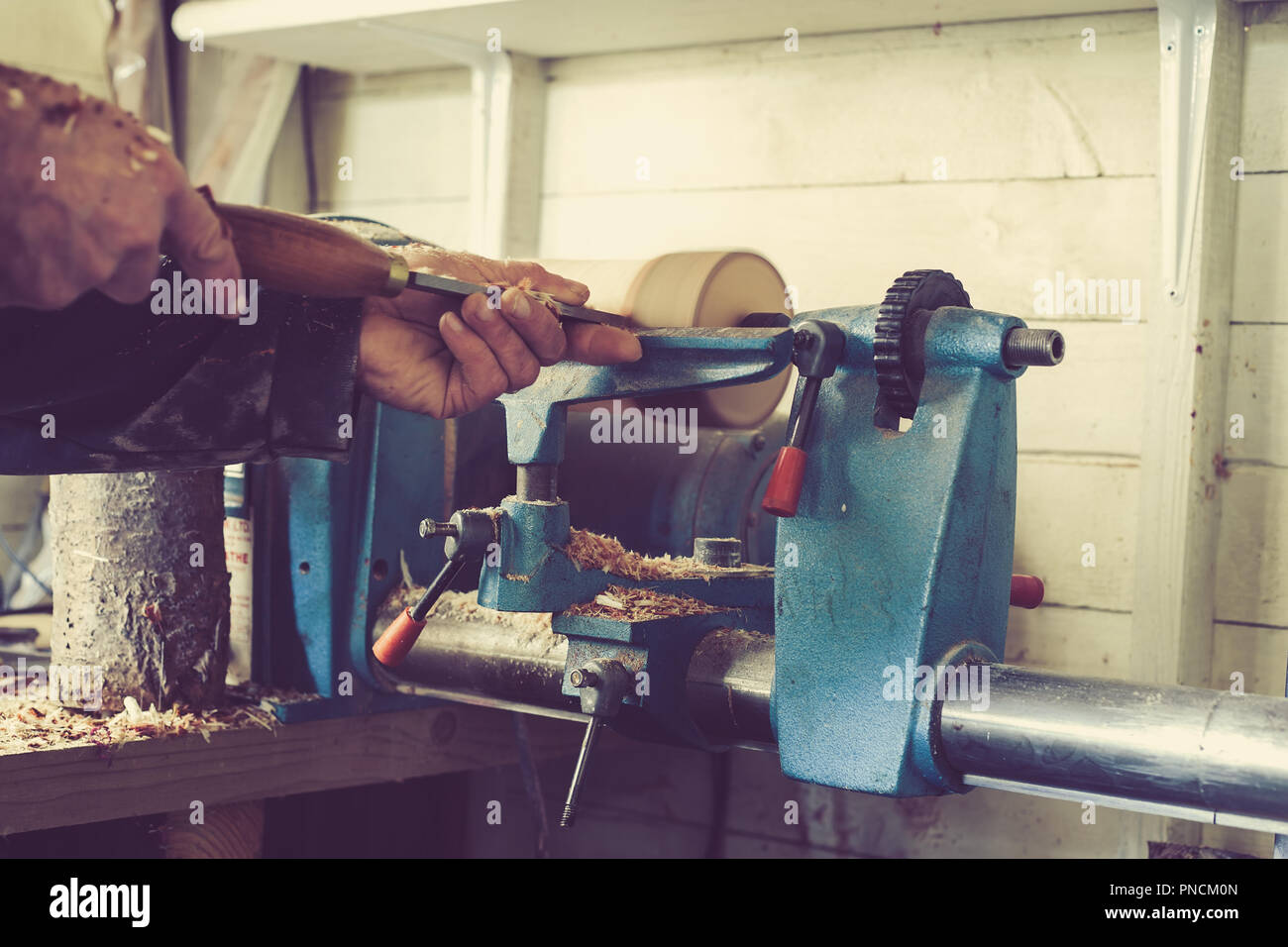 Man using old wood lathe turning wood, selective focus, dark toned ...