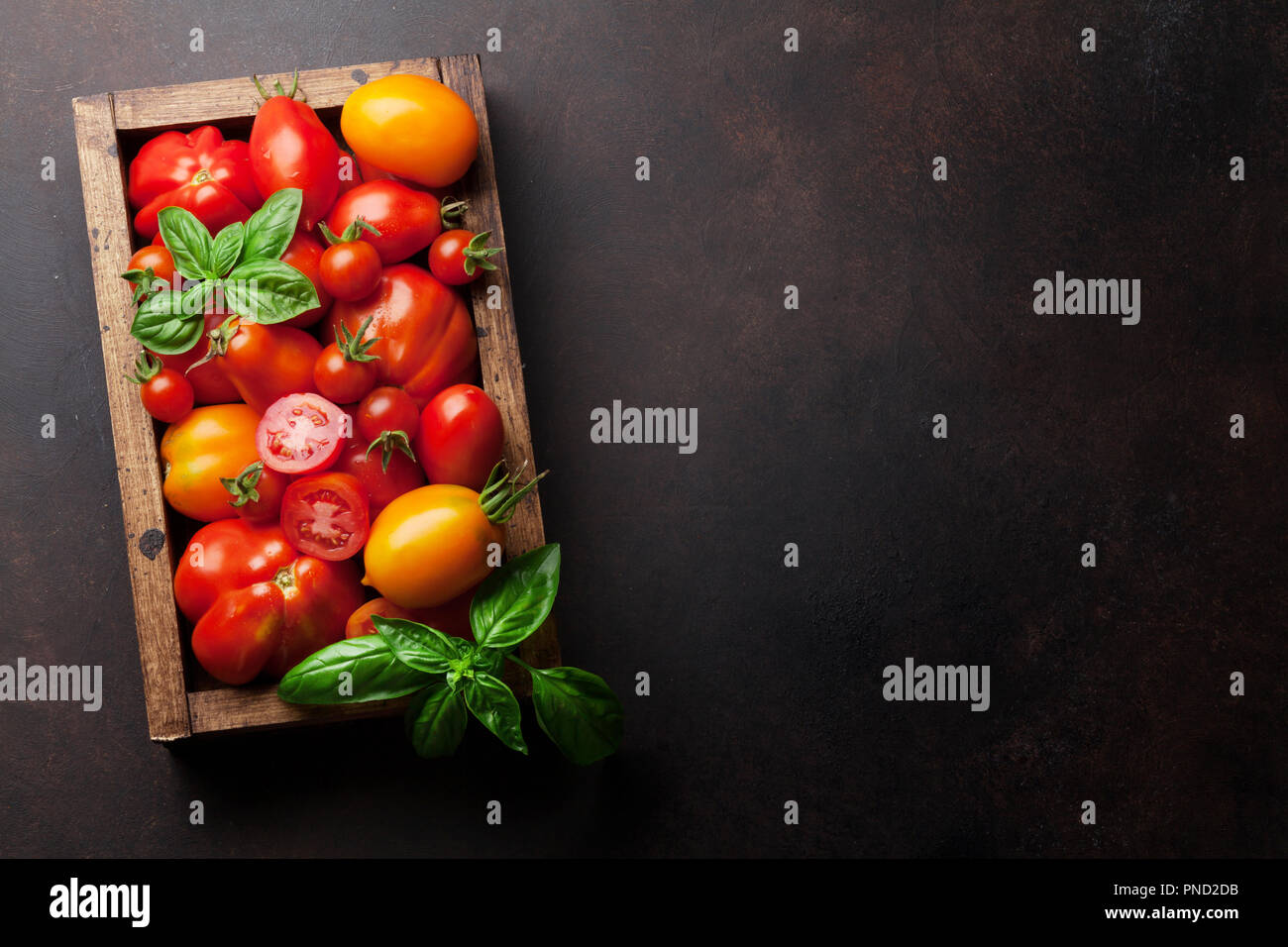 Fresh garden tomatoes and basil on cooking table. Top view with space ...