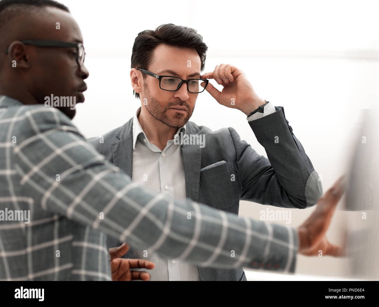 two serious businessmen talking standing in the office Stock Photo - Alamy