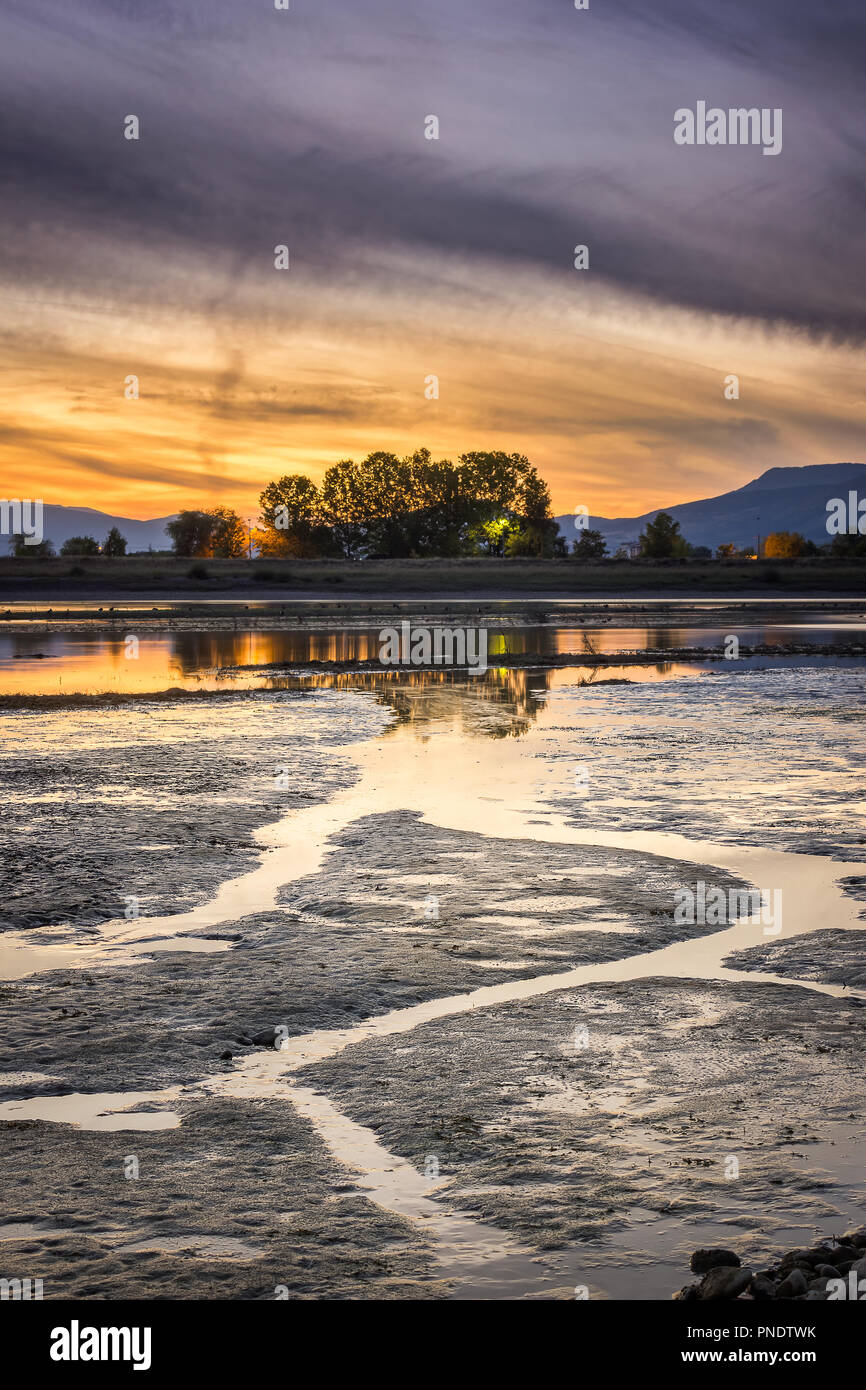 Muddy water flow patterns in dried up lake during colorful sunset ...