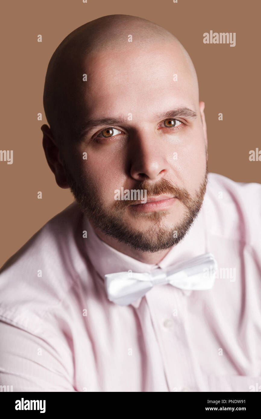 closeup portrait of handsome bearded bald man in light pink shirt and ...