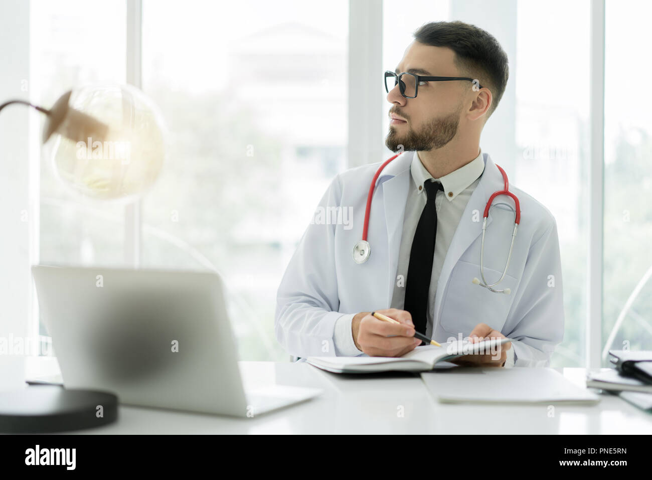 Doctor working with laptop computer and writing on paperwork with ...