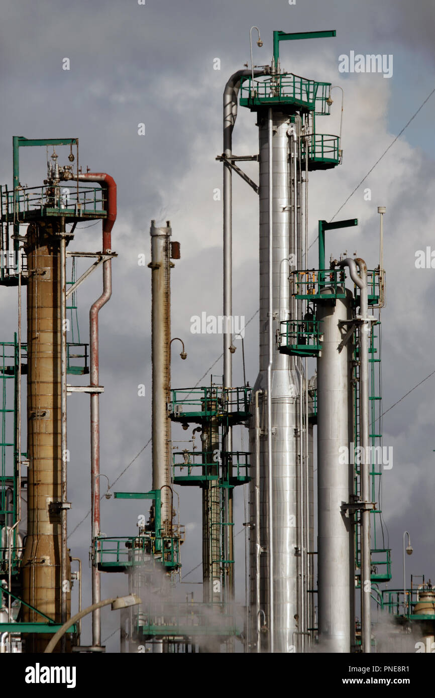 Industrial pipes and chimneys from a big oil refinery seeing steam and ...