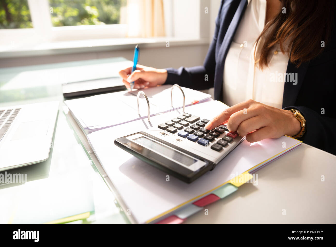 Businesswoman's Hand Calculating Invoice With Calculator In Office ...