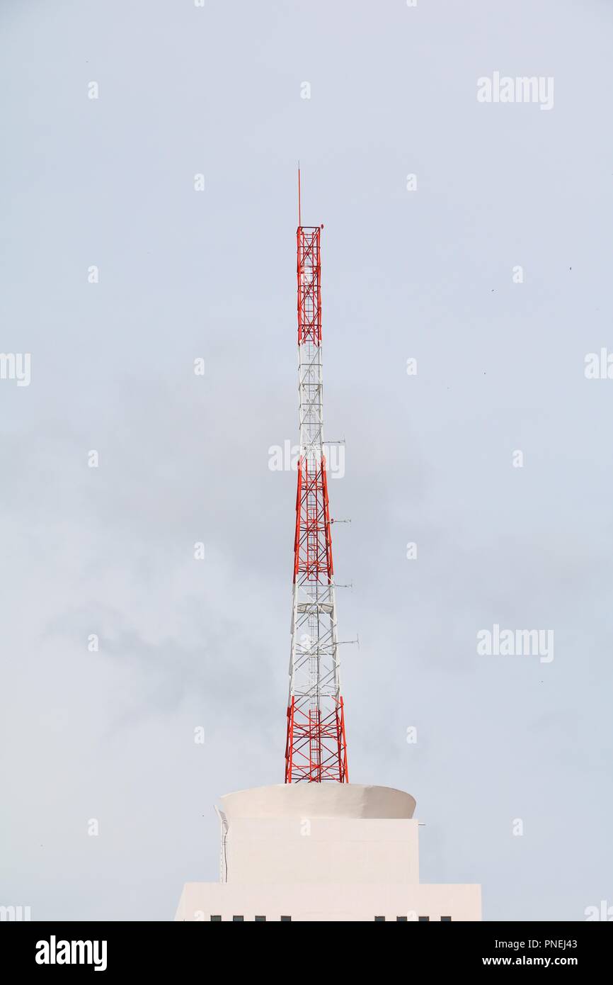 Telecommunication tower red and white antenna radio telephone mobile on building and sky ...