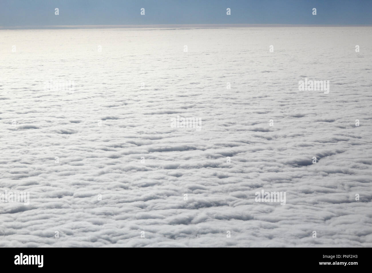 An areal view of flat uniform homogeneous clouds and a deep blue sky as ...
