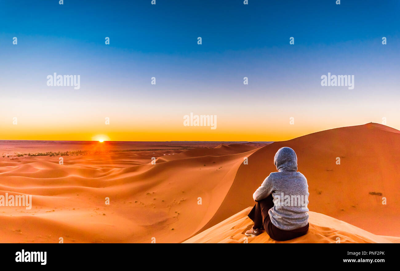 View on woman enjoing sunrise in the Sahara desert next to M'hamid in ...