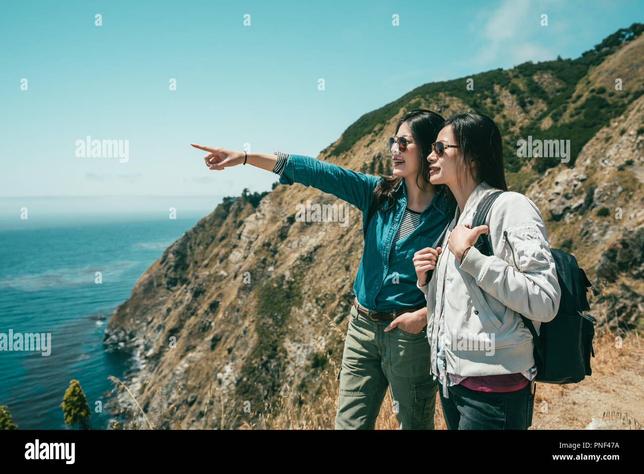 two beautiful women standing and pointing to somewhere while visiting ...