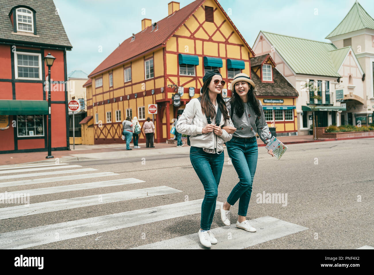 two good friends crossing the road and laughing with each other while ...