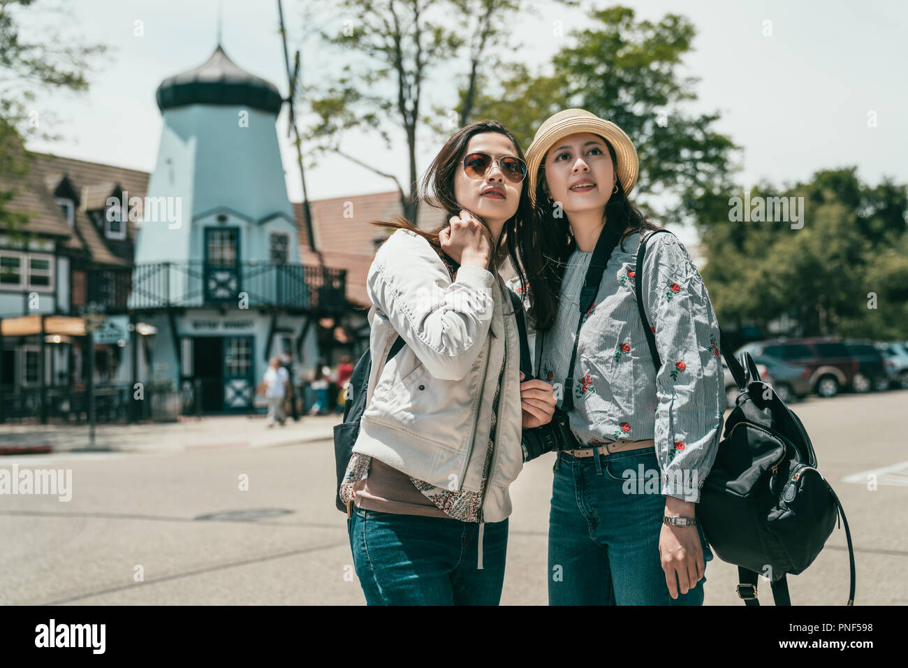 two pretty women standing in the corner and looking upward to somewhere ...