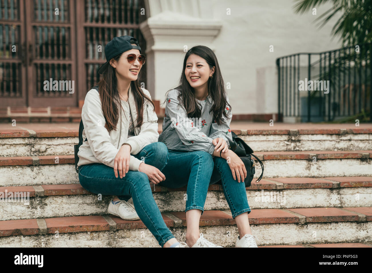 two good friends siiting on the stairs and laughing happily while ...