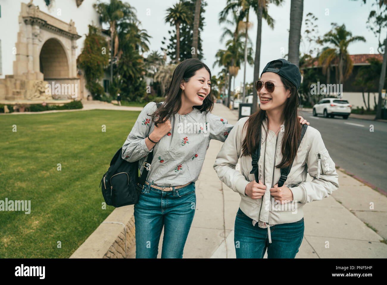 young pretty friends cuddling talking cheerfully while taking a walk on ...