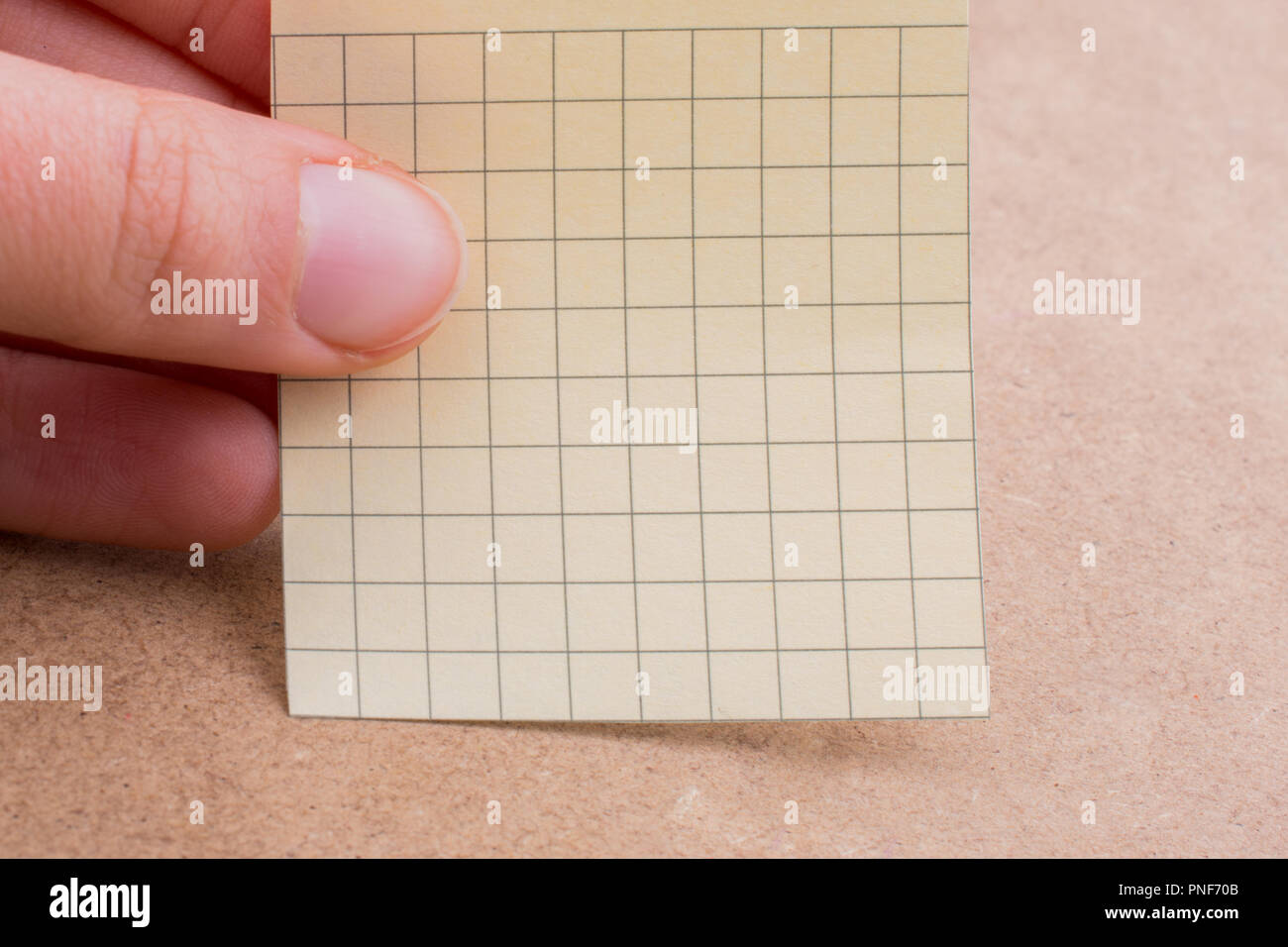 Hand holding a note paper on a brown background Stock Photo - Alamy