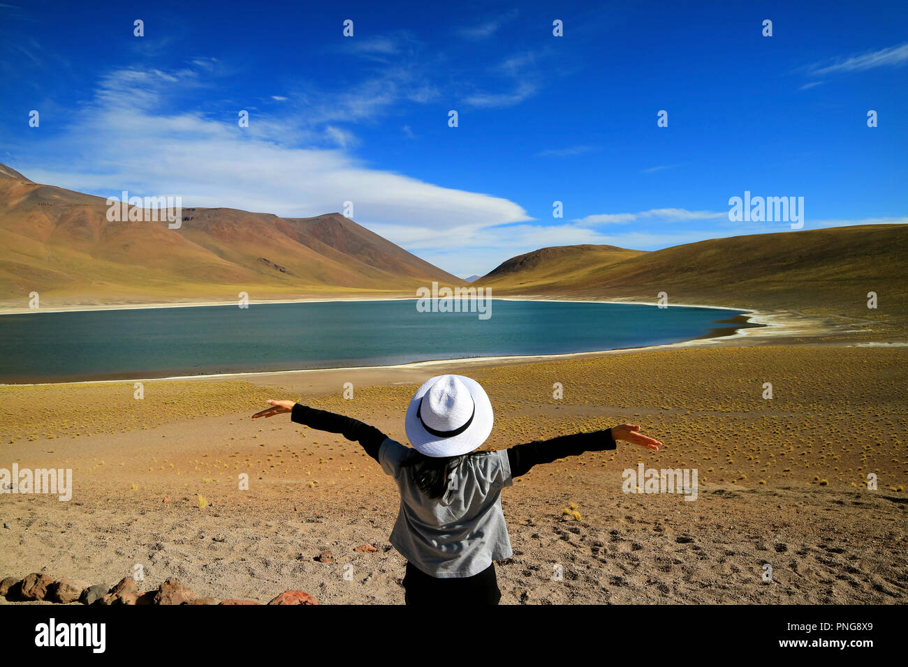 Female tourist raising her arms admiring the amazing deep blue lagoon ...