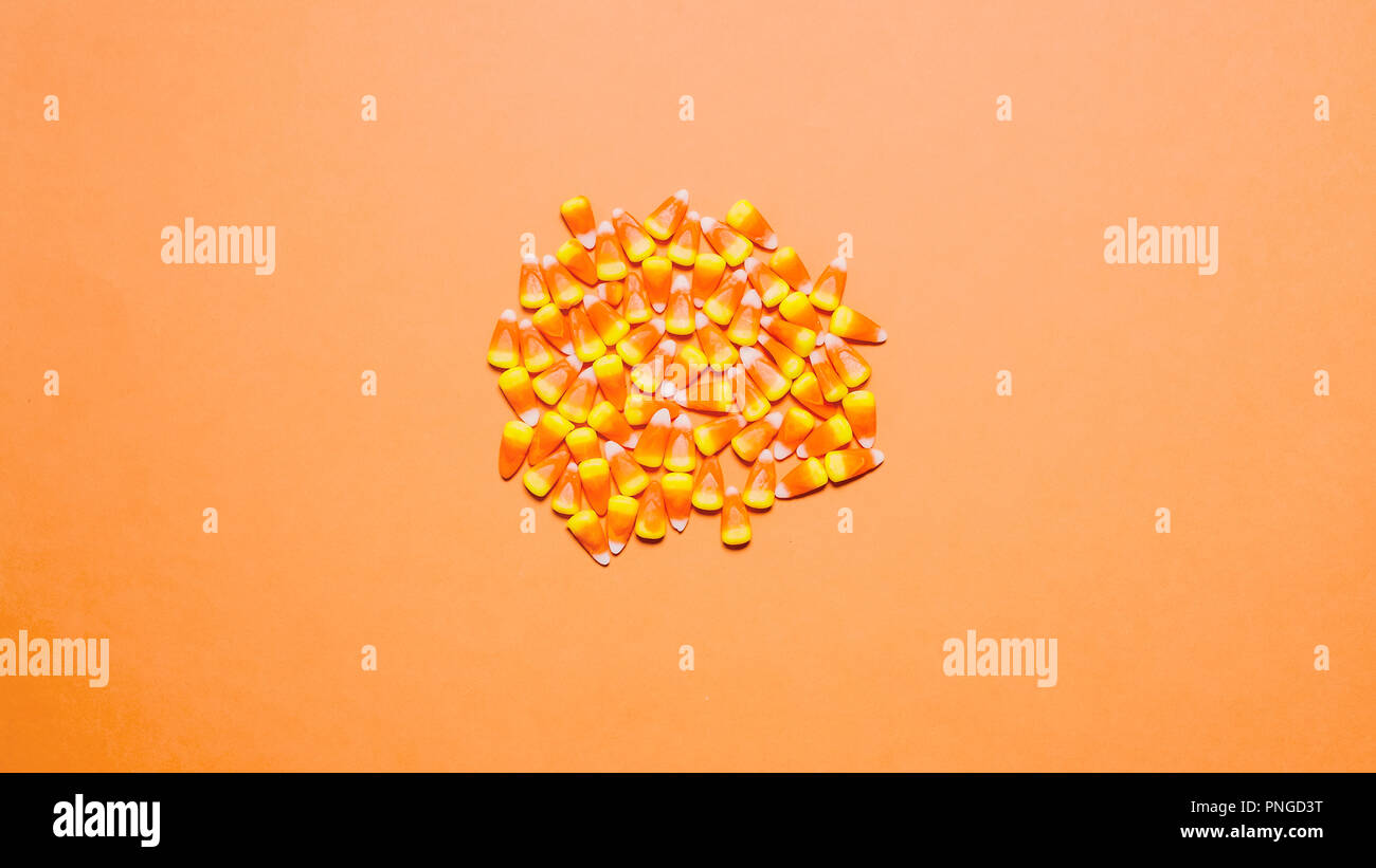 Candy corn scattered on an orange background with space for copy and ...