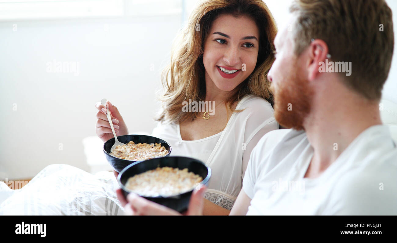 Happy married couple being romantic in bed sharing cereal Stock Photo ...