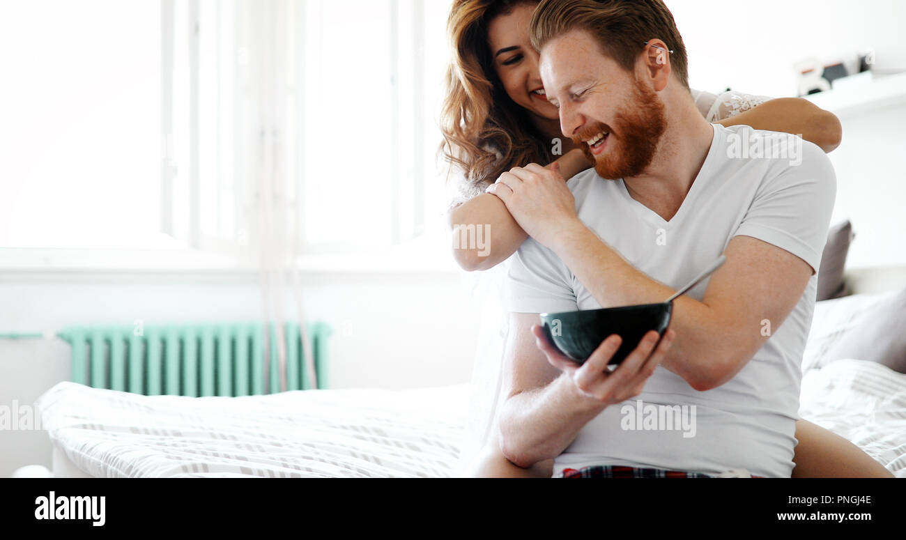 Happy married couple being romantic in bed sharing cereal Stock Photo ...