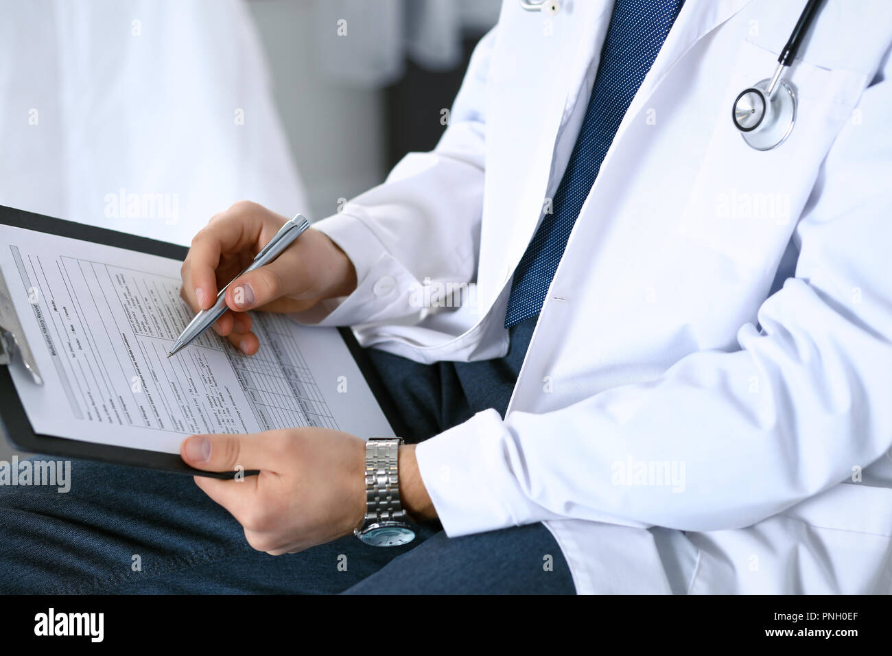 Doctor man filling up medical form on clipboard closeup. Healthcare ...