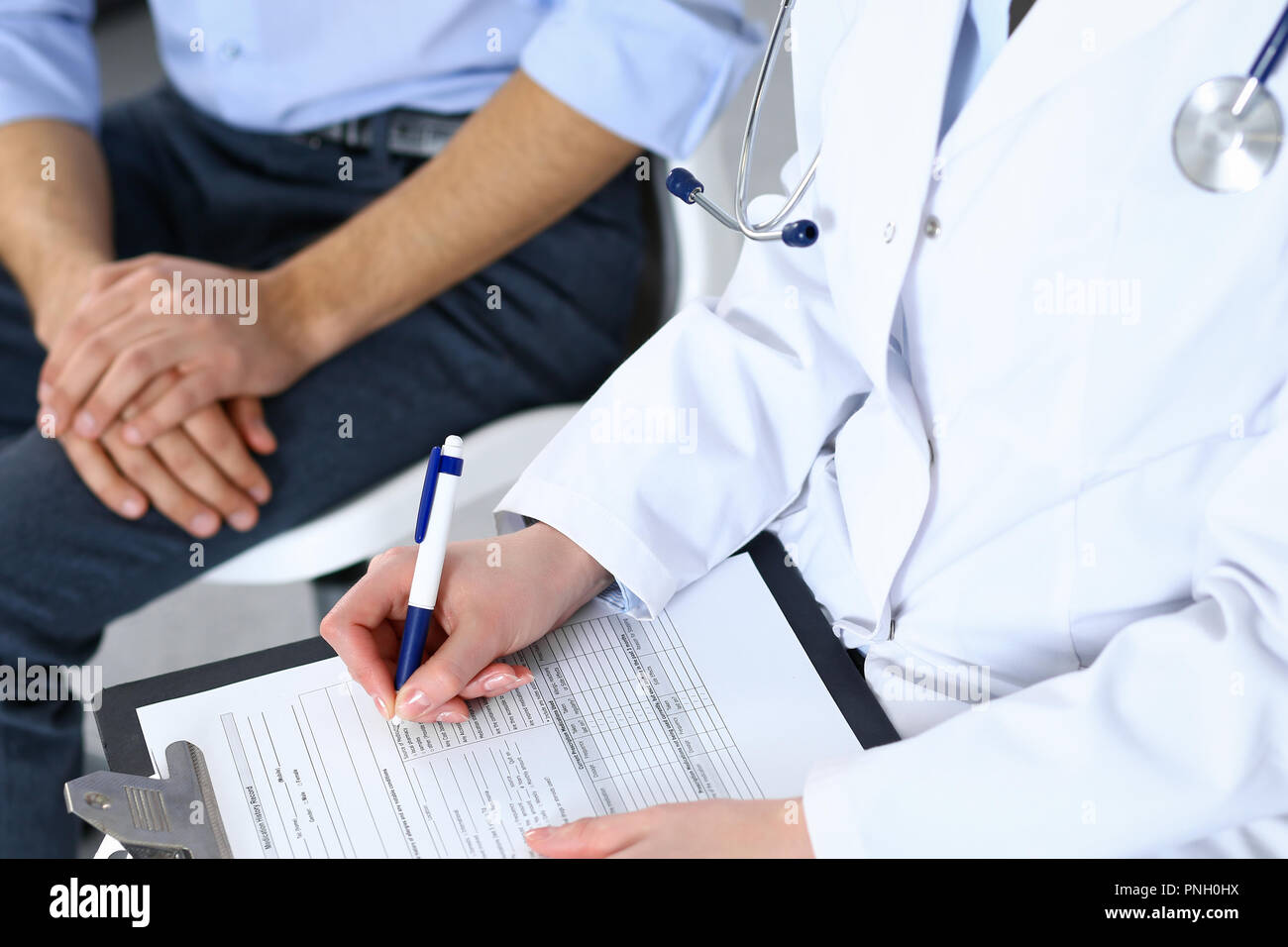 Female doctor holding application form while consulting man patient in ...