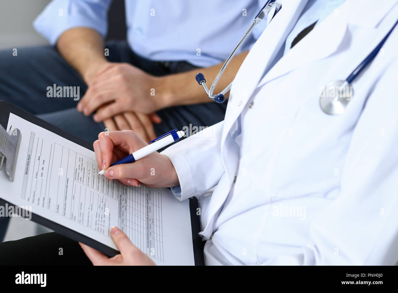 Female doctor holding application form while consulting man patient in ...