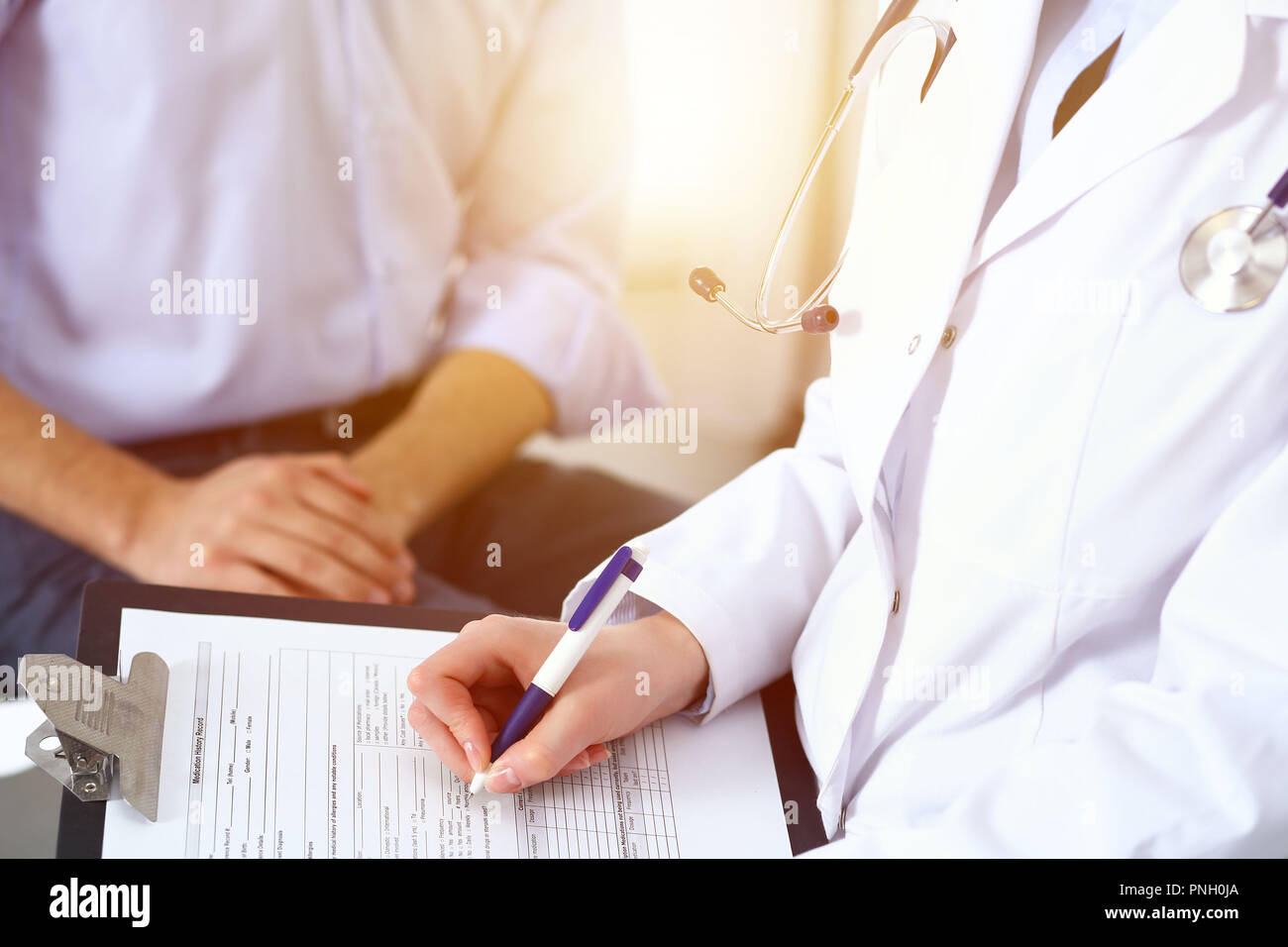 Female doctor holding application form while consulting man patient in ...