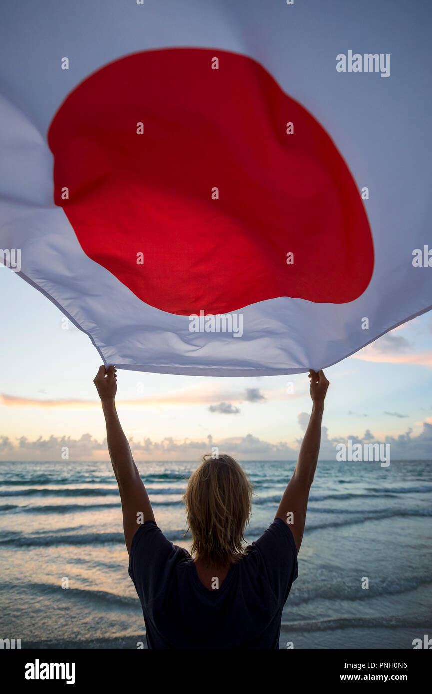 Man holding a fluttering iconic Japanese flag with circle of stars on ...