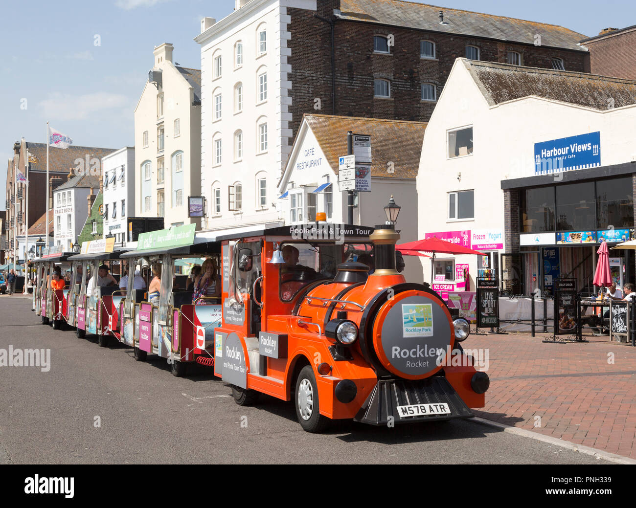 Rockley Rocket land train passing old historic buildings on quayside at ...