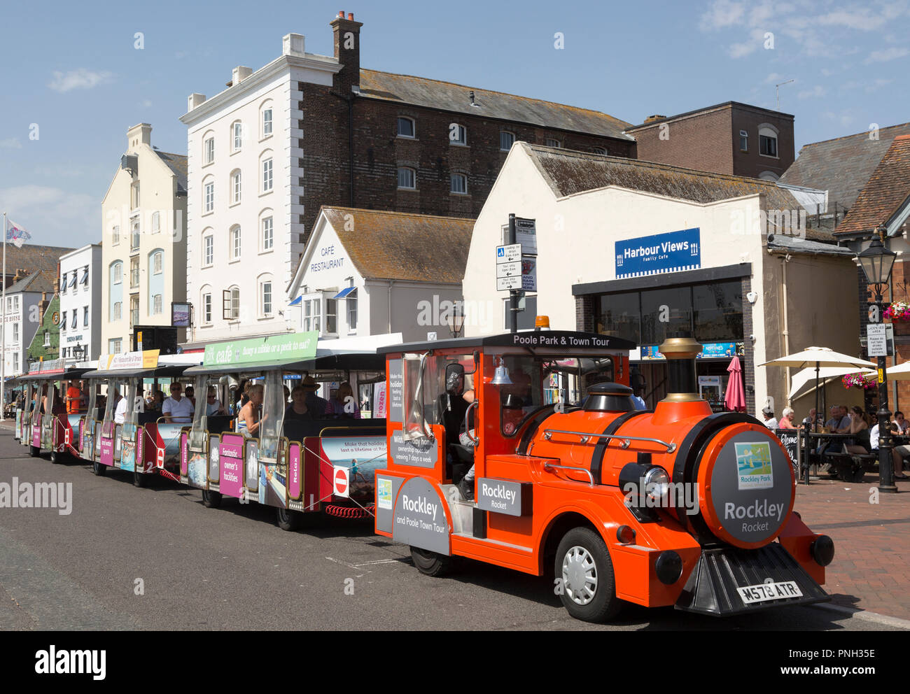 Rockley Rocket land train passing old historic buildings on quayside at ...