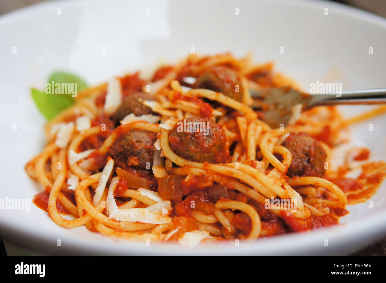 A plate of spaghetti with meat sauce in a large white bowl. Atop of the ...