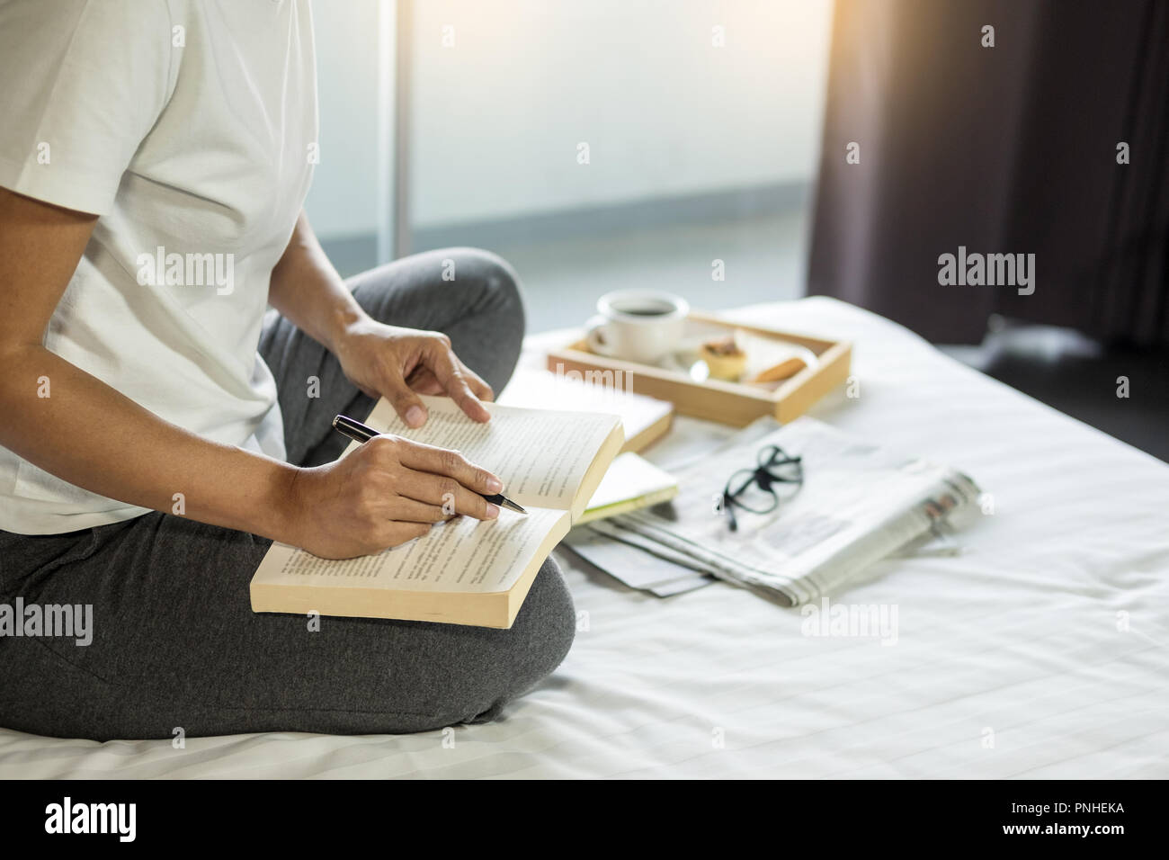Young woman sitting working and writing in the notebook on bed leisure ...
