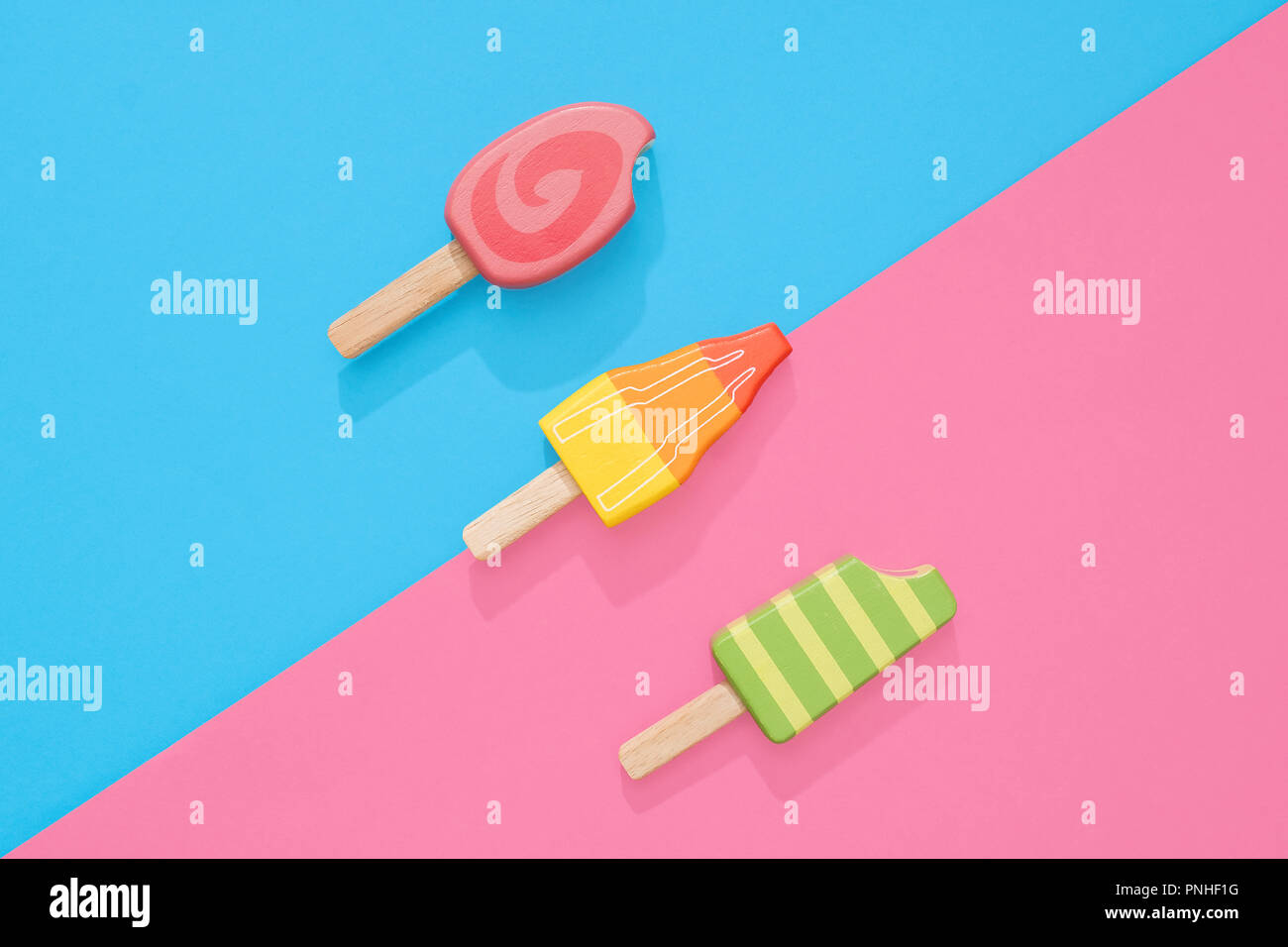 Assorted wooden toy ice lollipop popsicles on a split coloured pastel ...