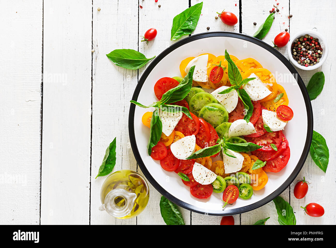 Mozzarella cheese, tomatoes and basil herb leaves in plate on the white ...