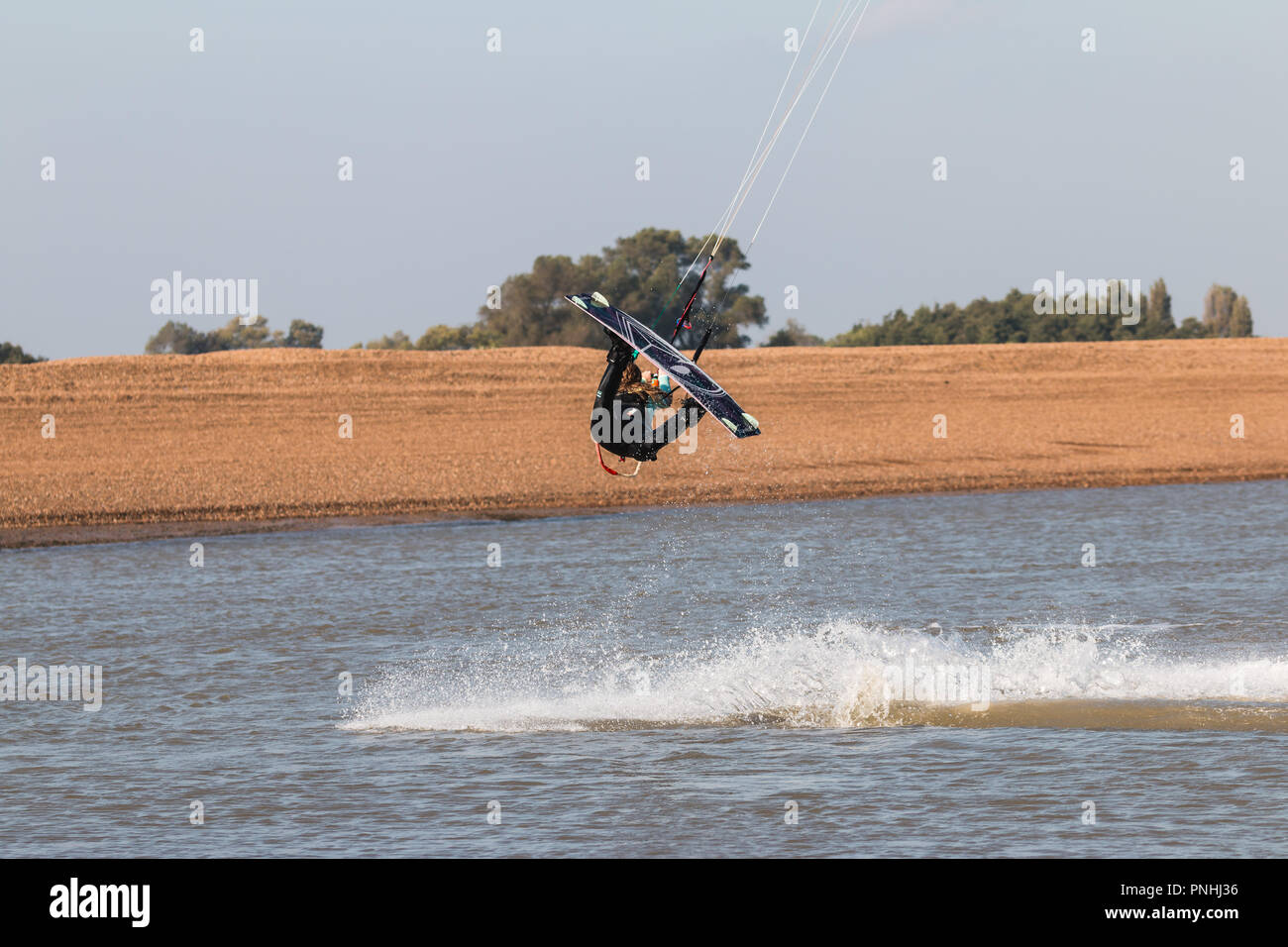 Kiteboarder pulling tricks and getting air on a bright summers day with ...