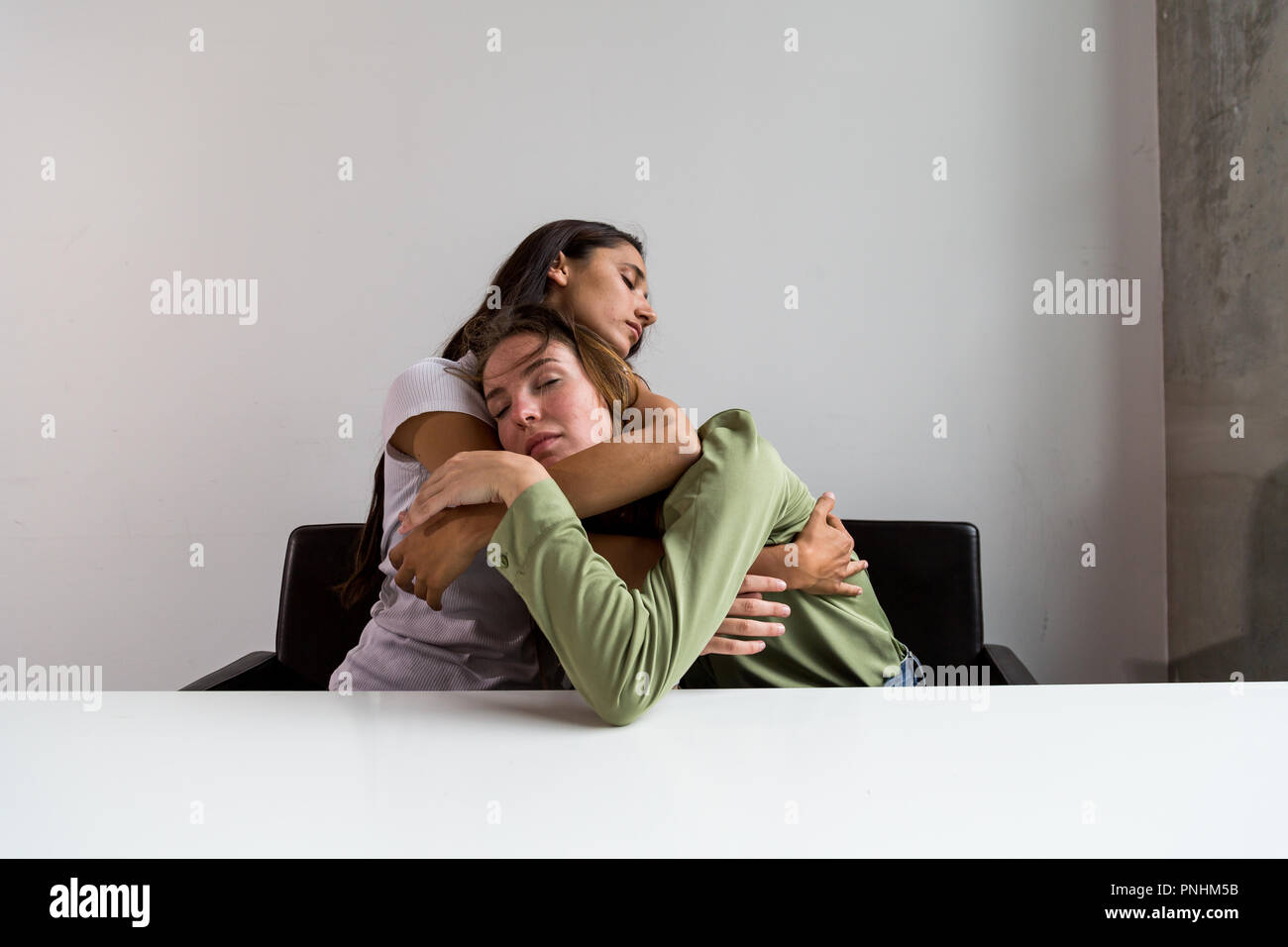 Two women performing artistic poses seated at large bureau. Loving ...