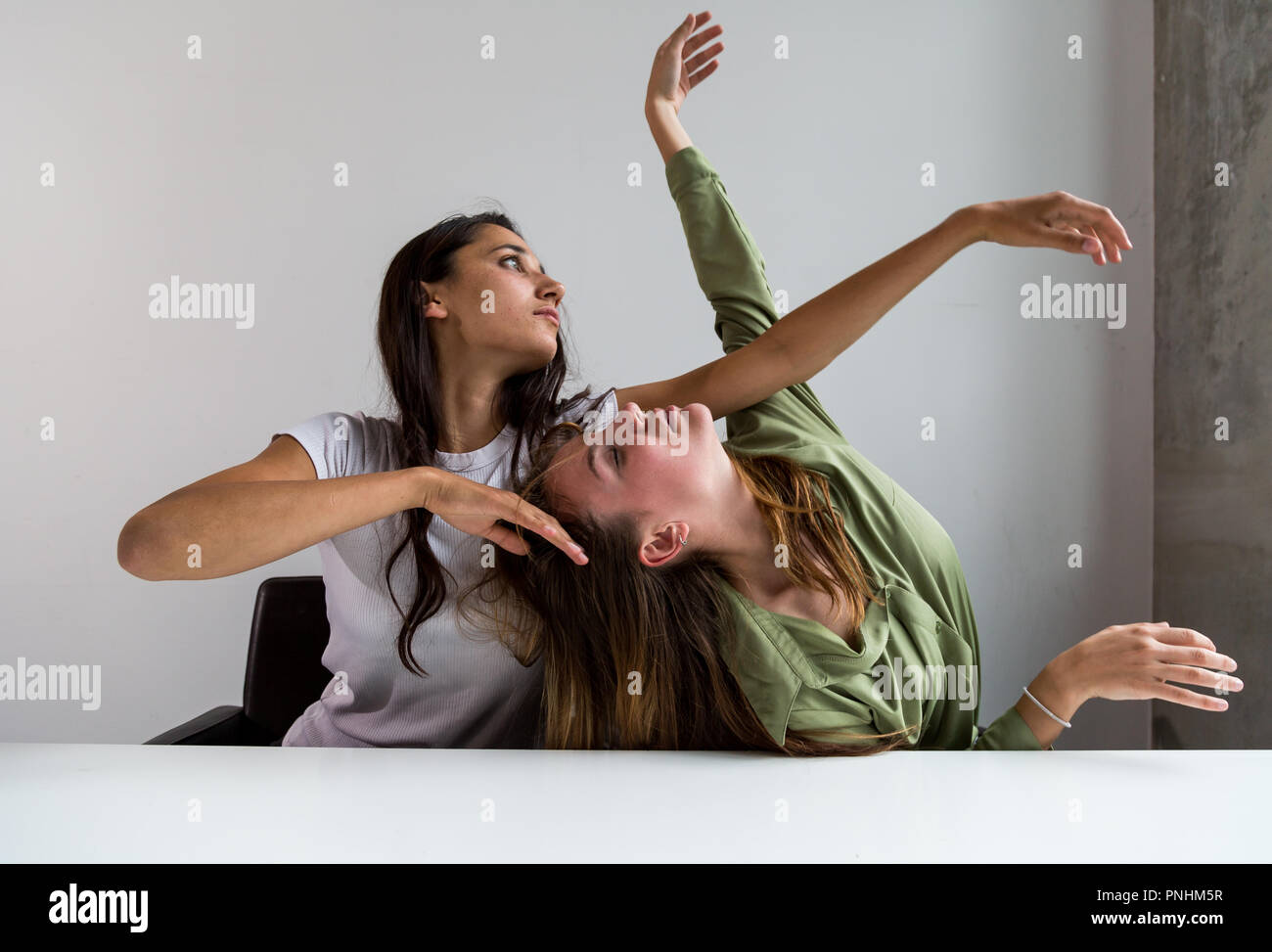 Two women performing artistic poses seated at large bureau. Dancing ...