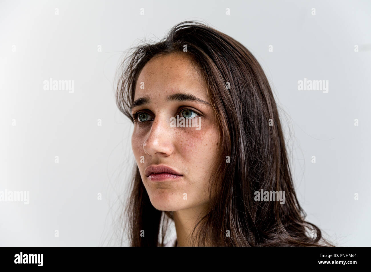 Face portrait of a mixed race young woman in front of a white wall ...