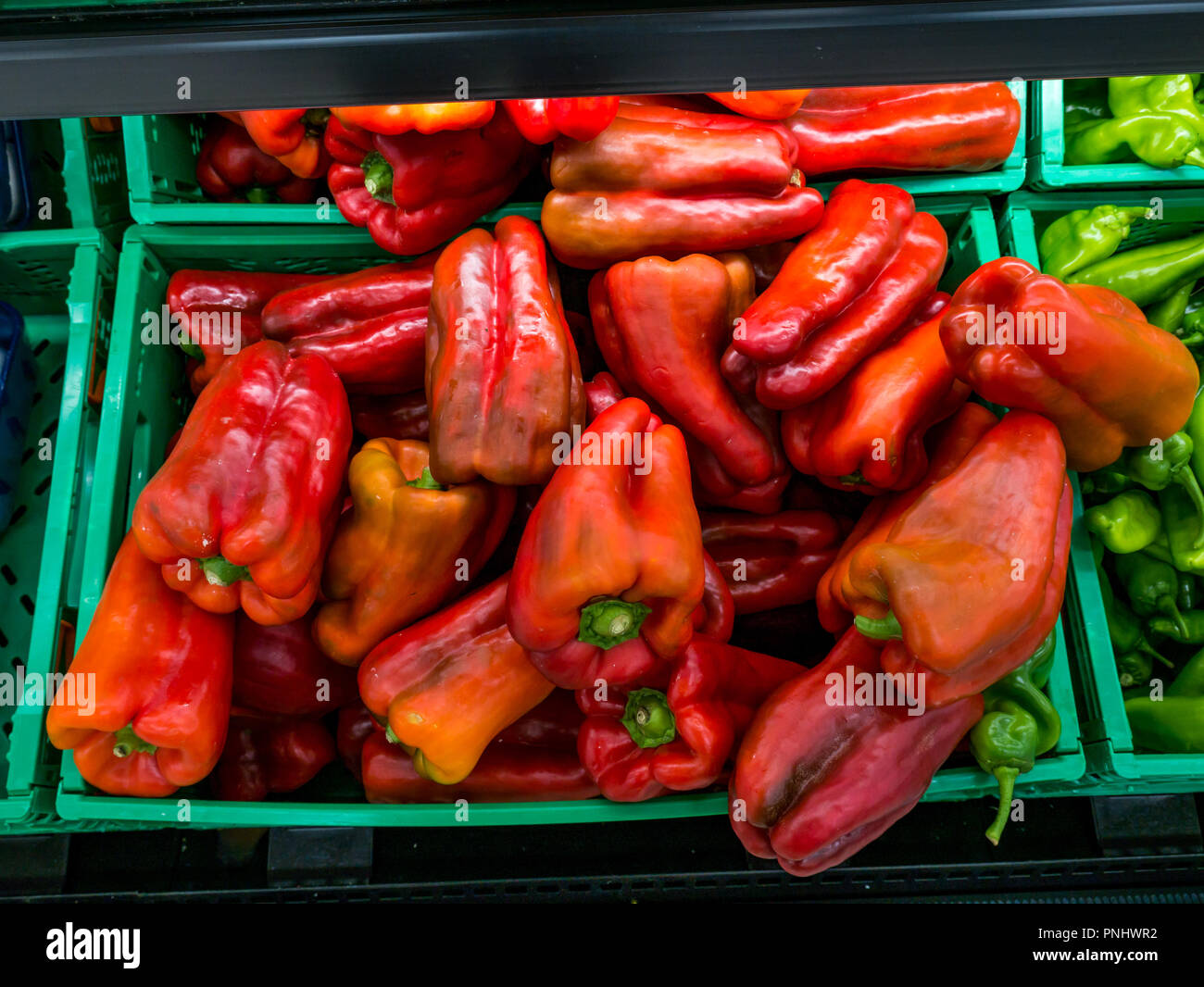 Close up of large red peppers in vegetable box in supermarket aisle ...