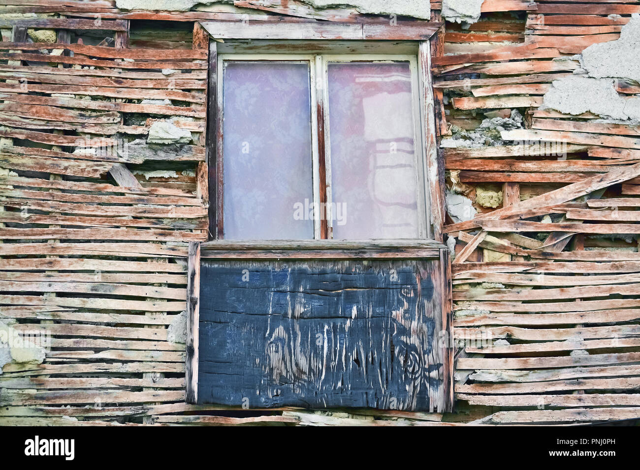 Detail of a rotting house and dilapidated wooden window made of planks ...